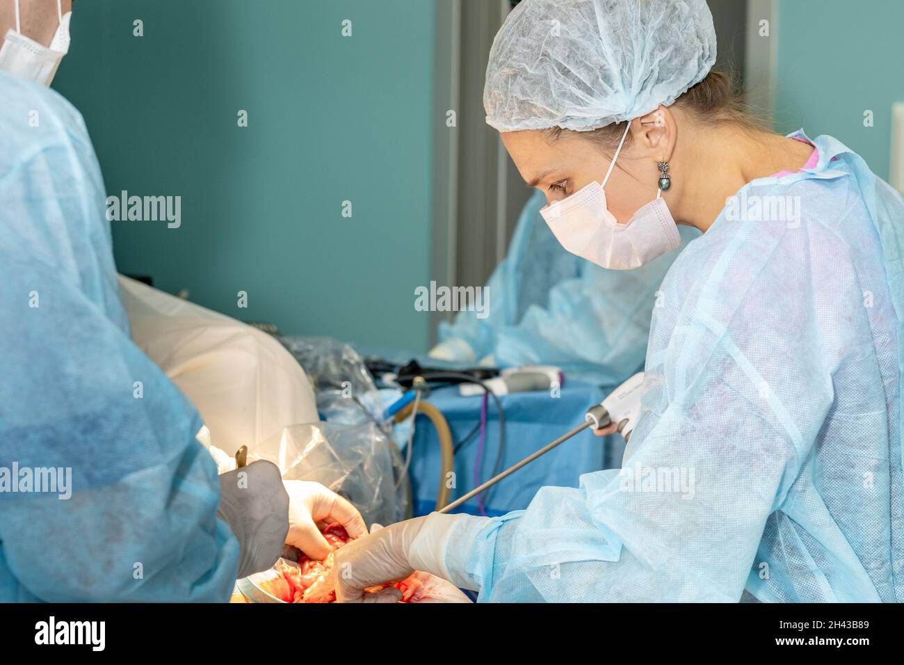 A surgeon in a sterile uniform and a surgical mask performs a surgical ...