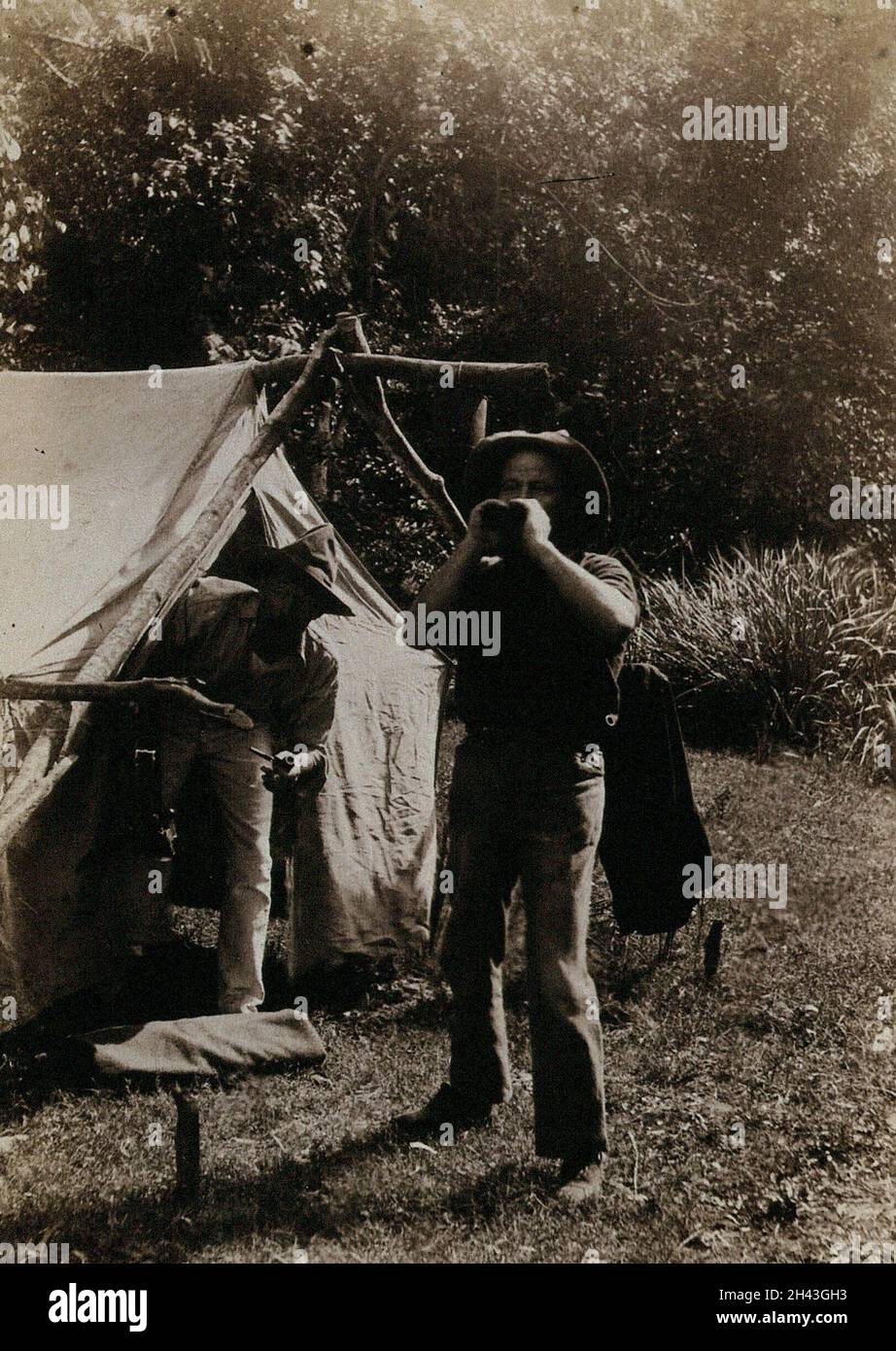 Two men outside a crude tent, one shouting (?) Photograph, ca.1900 ...