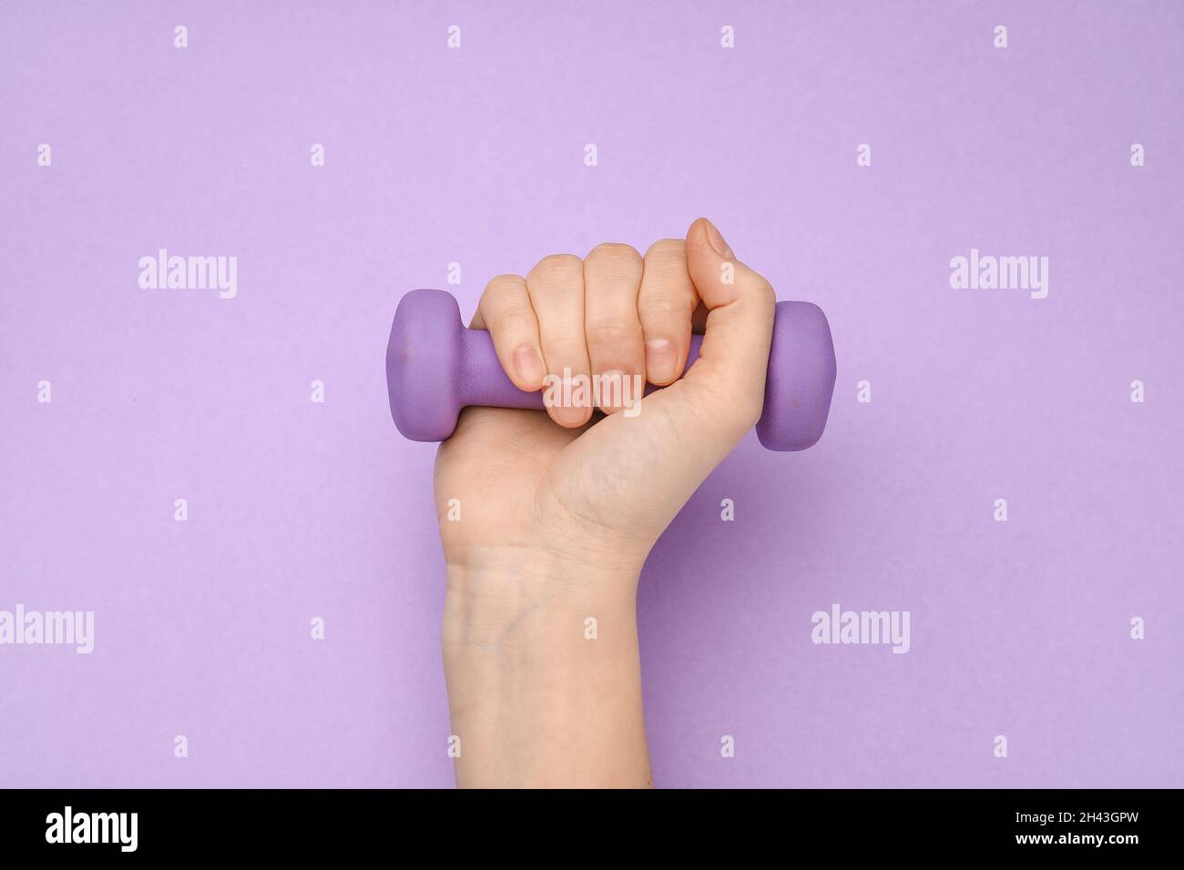 Female hand with dumbbell on purple background Stock Photo - Alamy