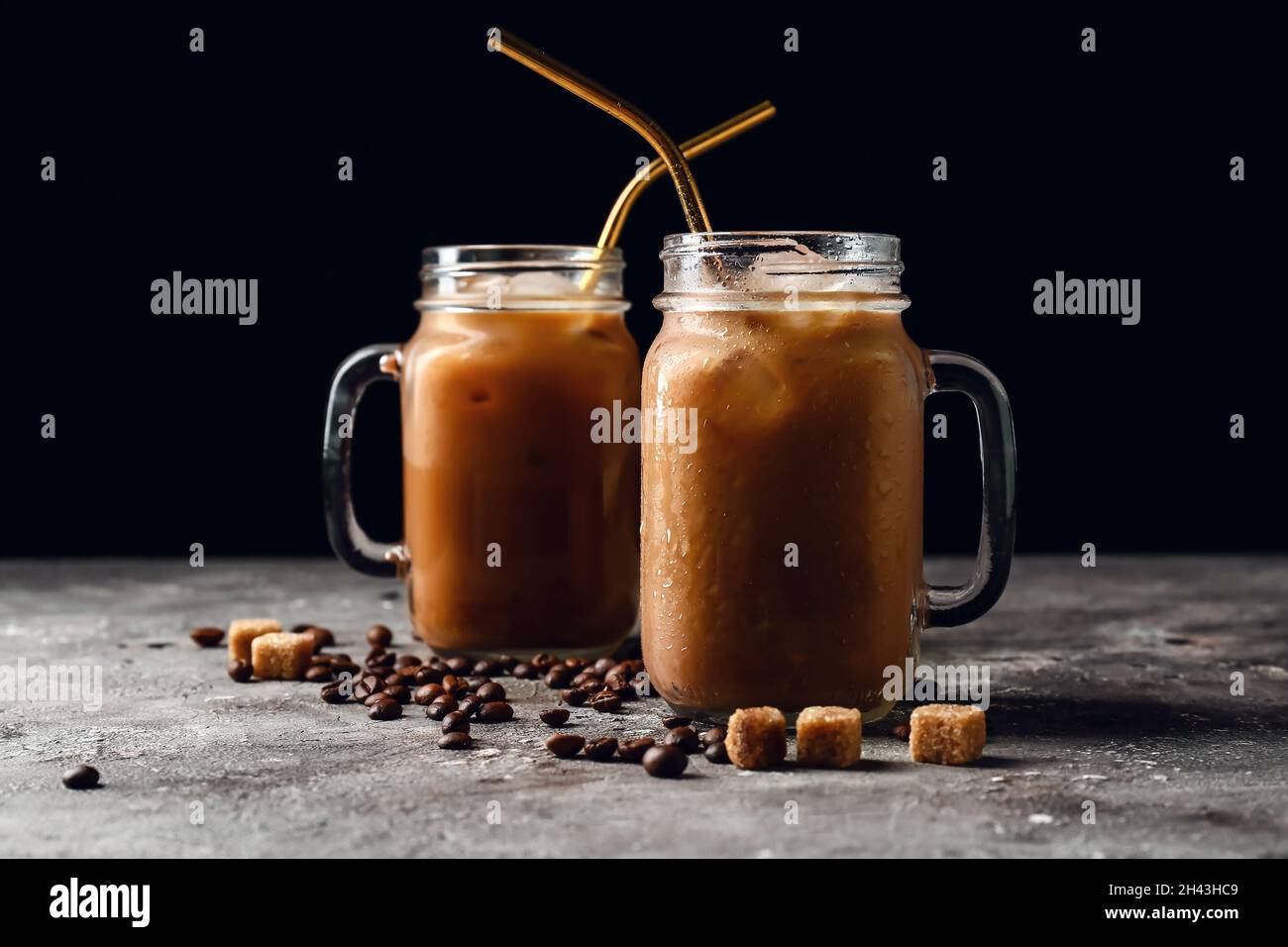 Mason jars of tasty iced coffee with milk, beans and sugar cubes on ...