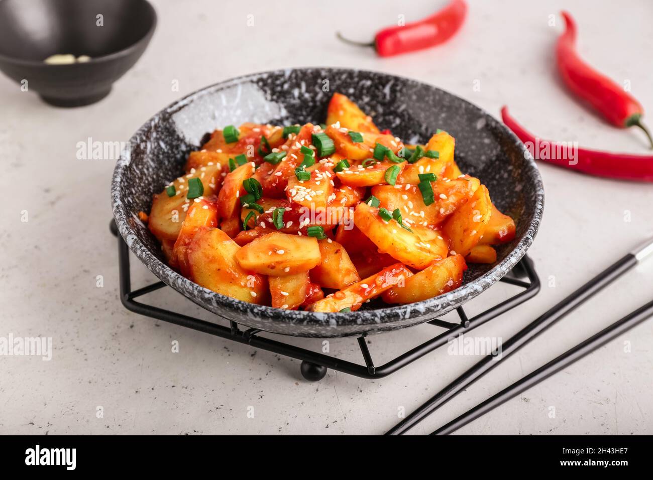 Plate with honey chilli potato and chopsticks on light background Stock ...