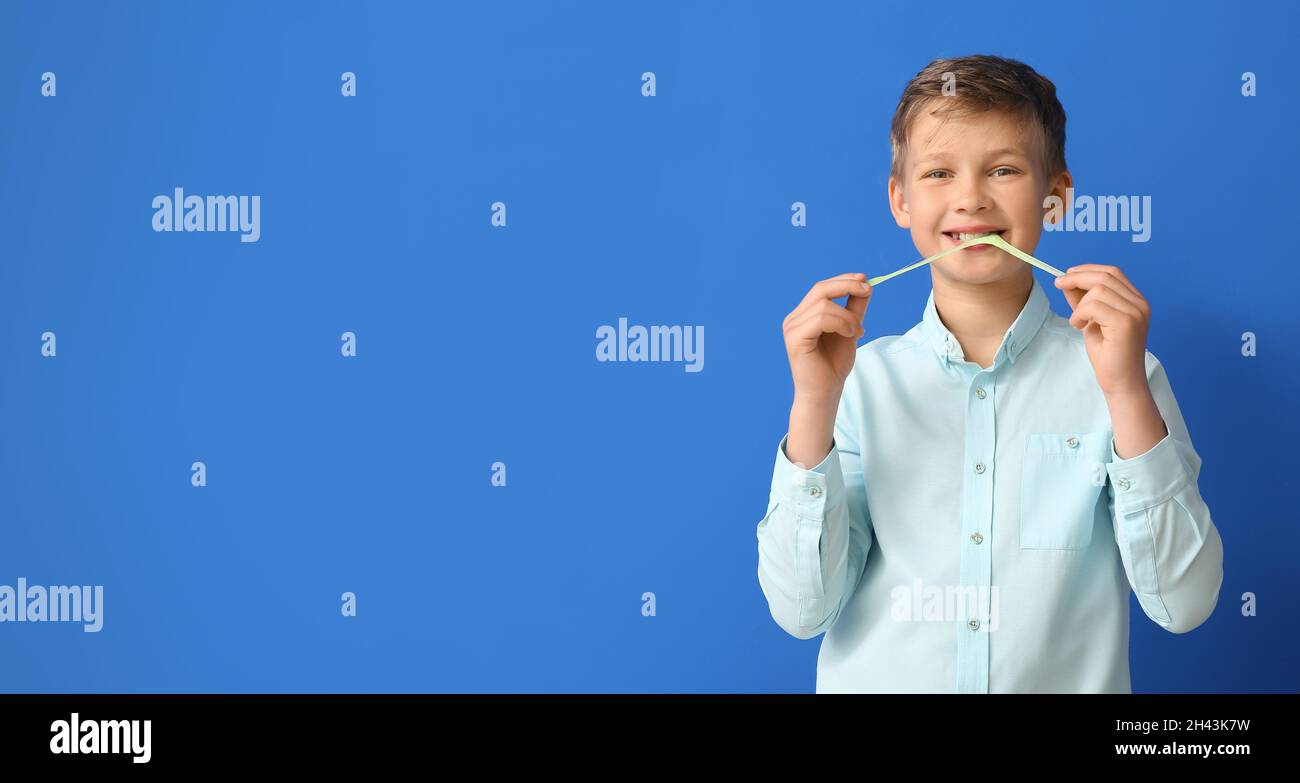 Cute little boy chewing gum on blue background Stock Photo - Alamy
