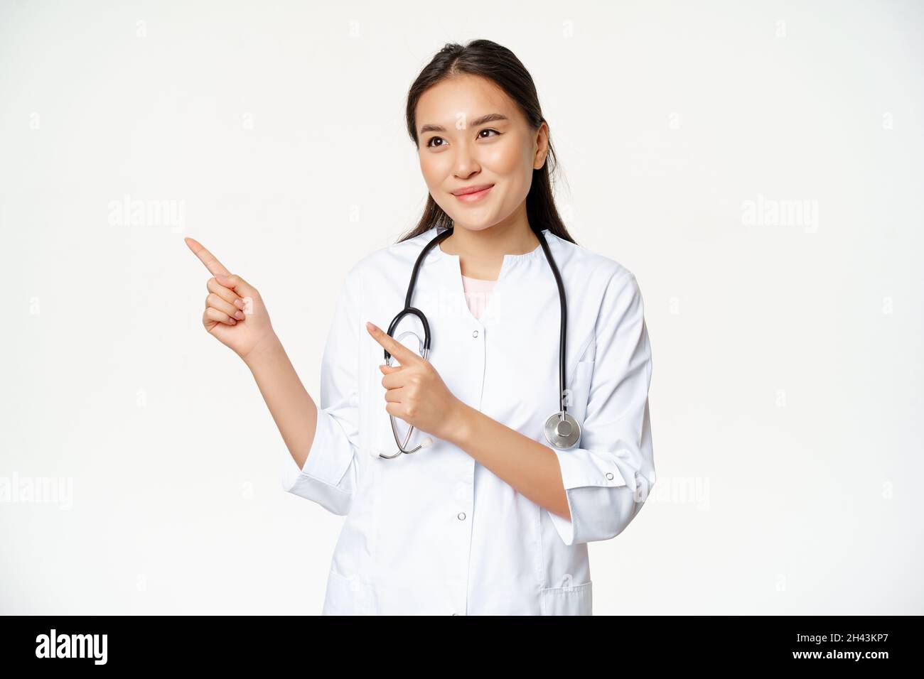 Pleasant smiling female doctor in uniform, pointing fingers and looking ...