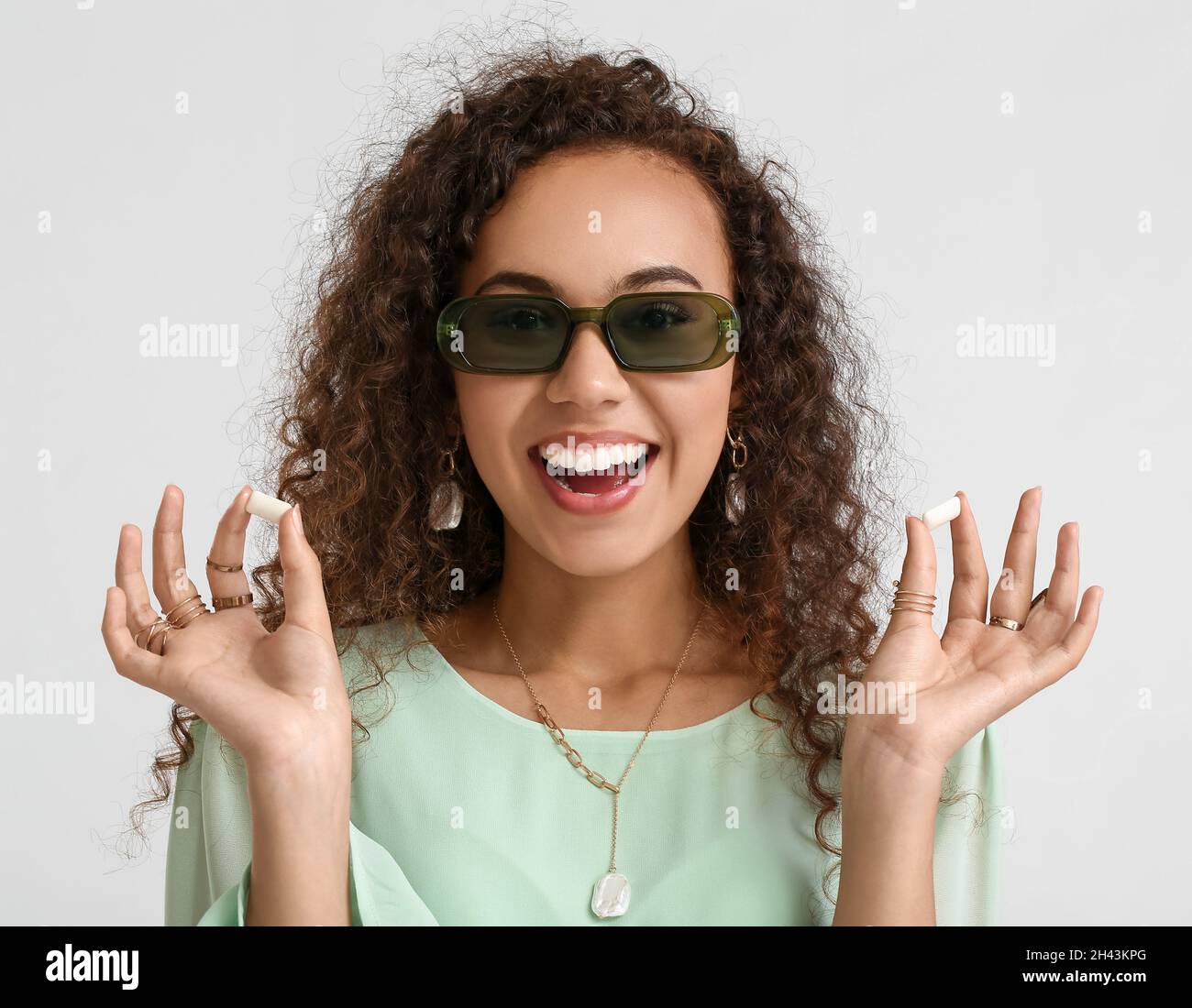 Cool African-American woman with chewing gum on light background Stock ...