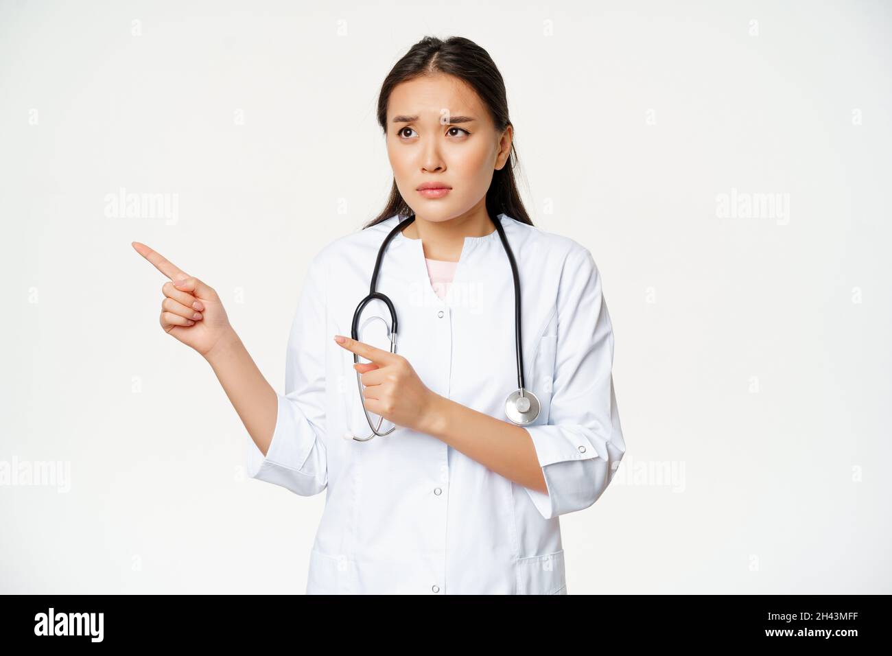 Skeptical female doctor, concerned nurse pointing and looking left with ...