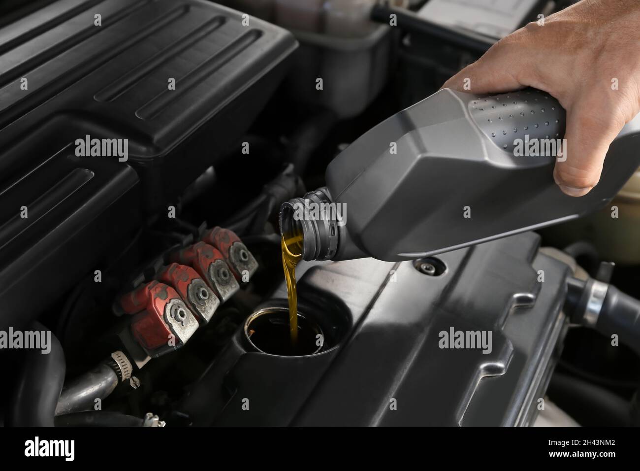 Male mechanic pouring motor oil from canister into car engine Stock ...