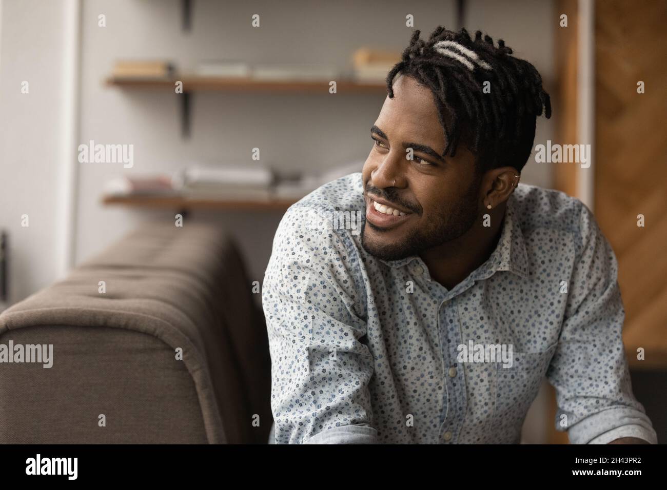 Happy young african ethnicity man dreaming resting on sofa Stock Photo ...