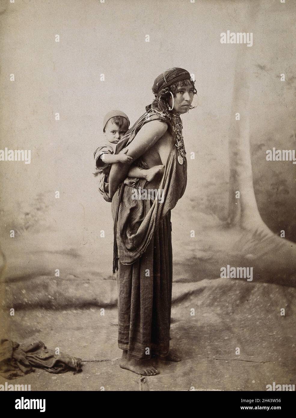 Tunisia: a Bedouin woman carrying her child on her back: studio ...
