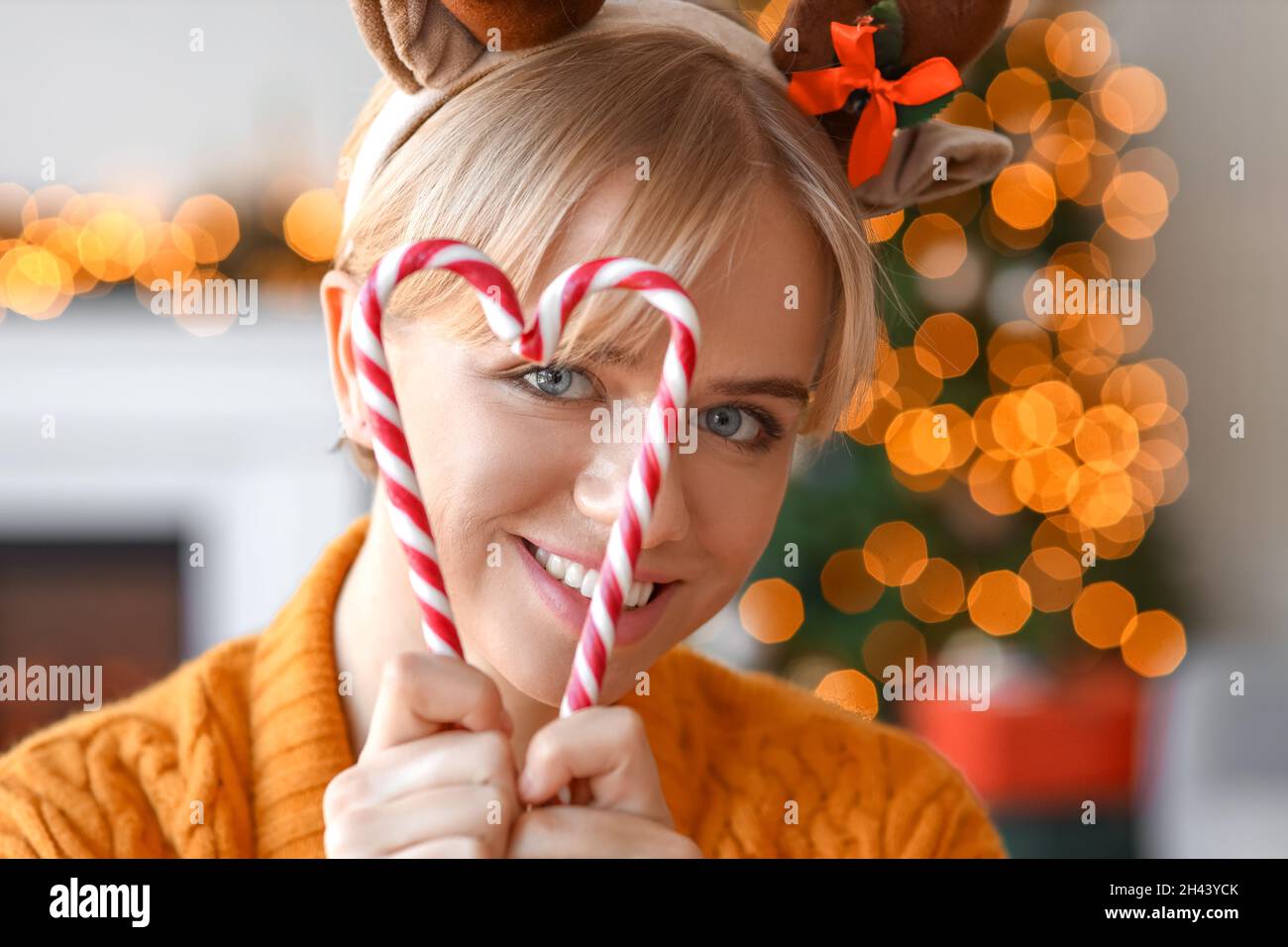 Beautiful young woman with candy canes at home on Christmas eve Stock ...