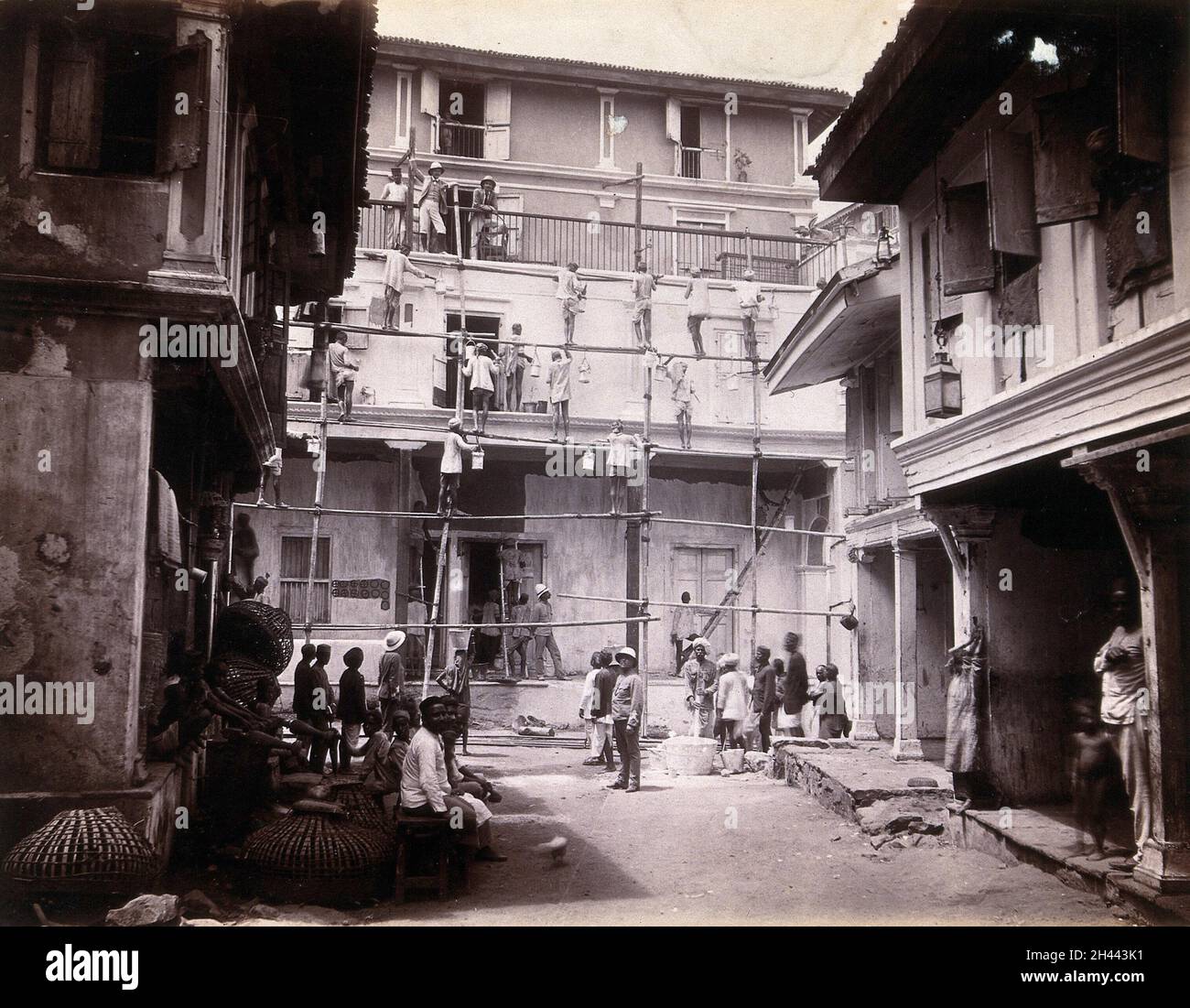 A plague house being whitewashed by men standing on scaffolding in ...