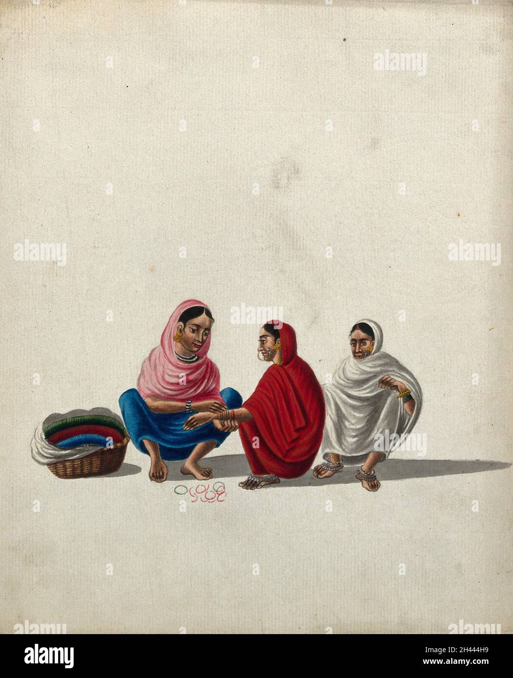 A woman selling bangles, helps a customer to try on some bangles ...