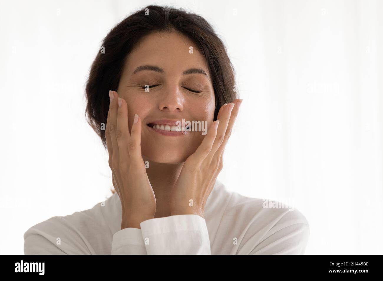 Young beautiful woman reflected in mirror touch face skin Stock Photo ...
