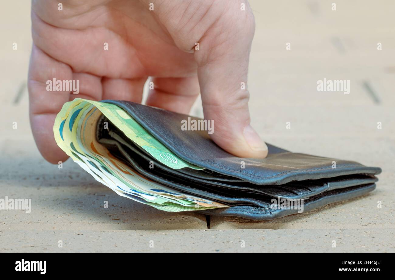 Hand grabs wallet from street floor Stock Photo - Alamy