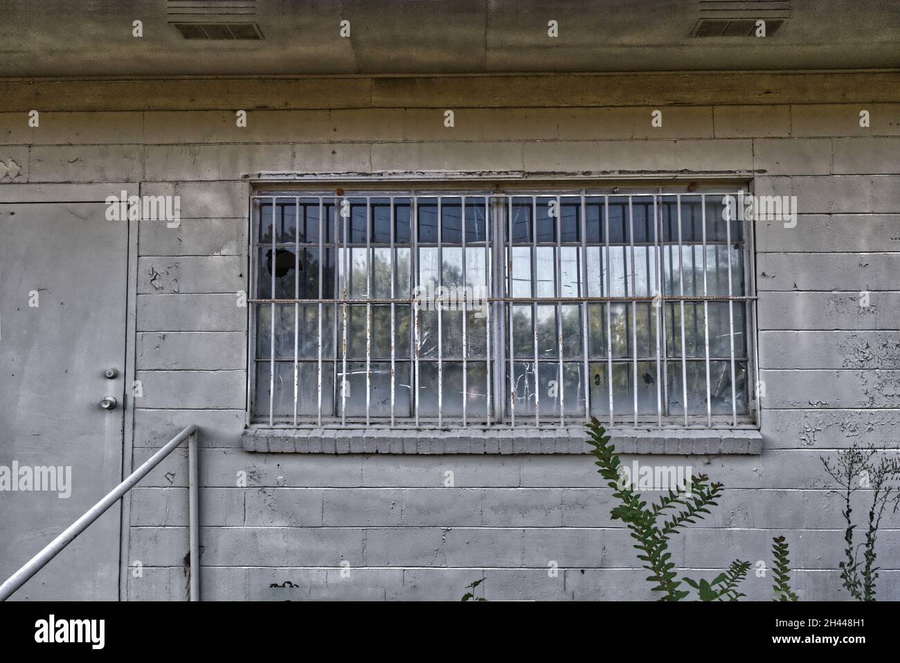 Old vintage white brick building abandoned gated windows in rural ...