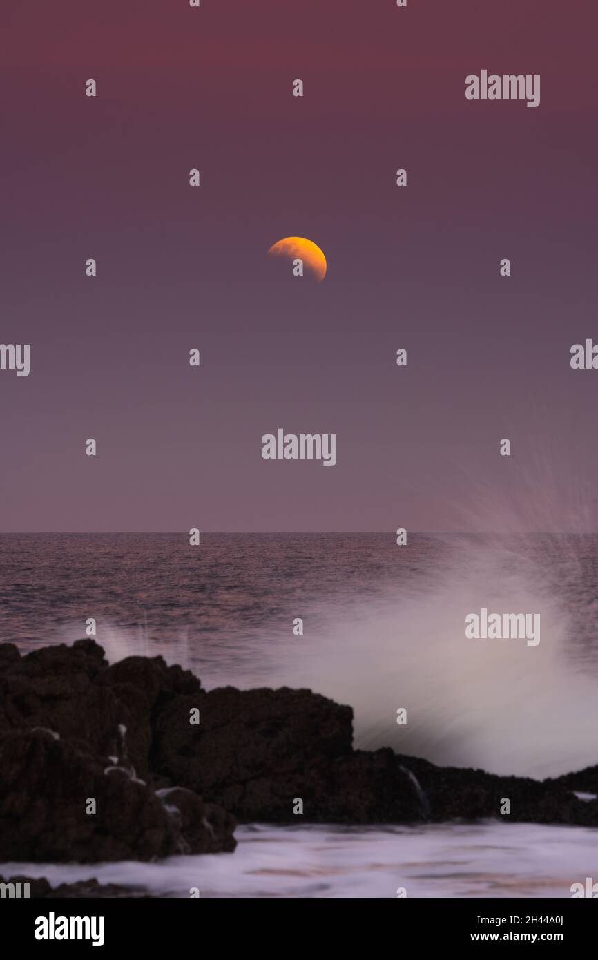 The first glare of the moon over the splashing sea water at sunset ...