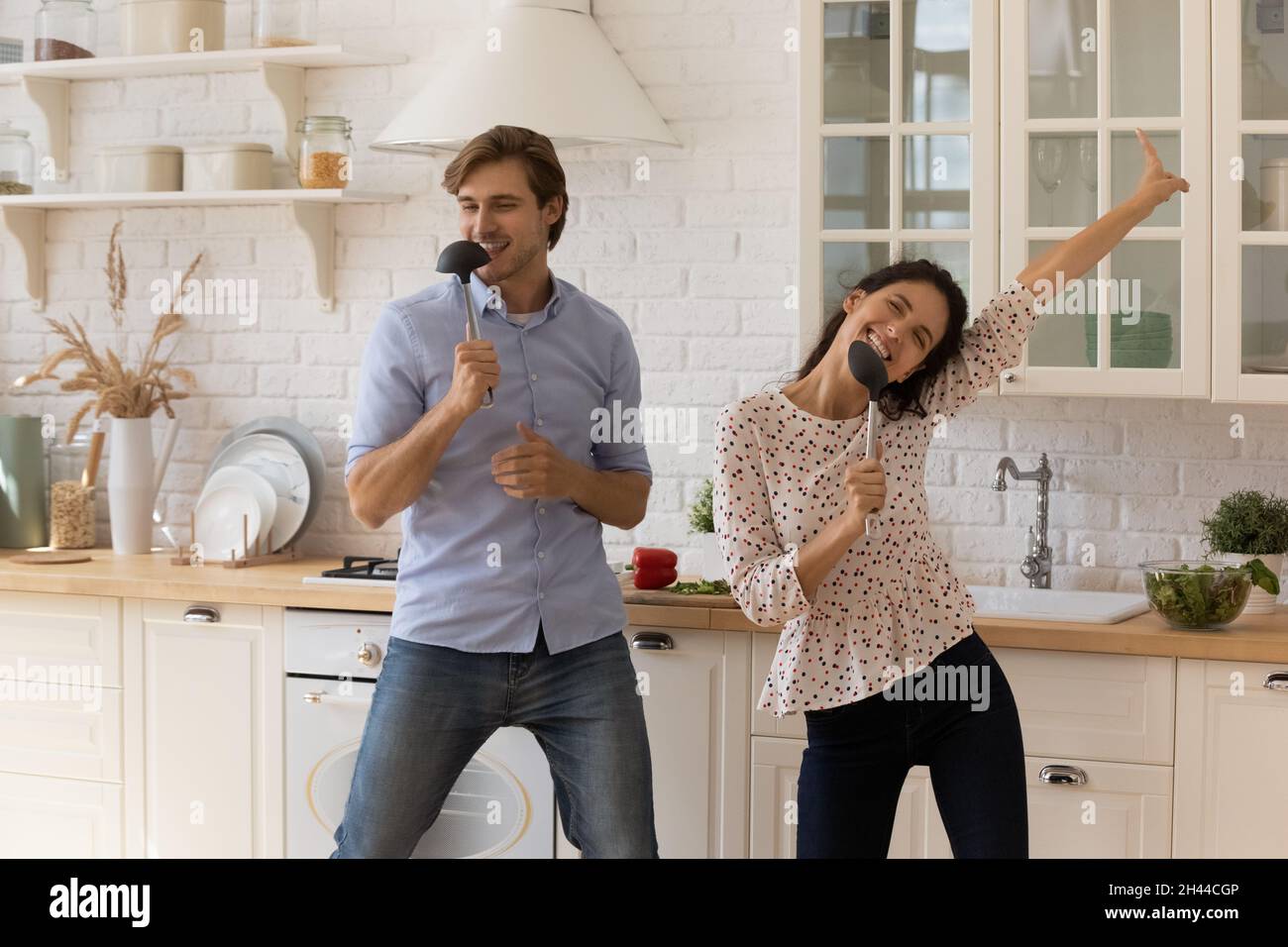 Lively attractive young couple singing dancing in kitchen Stock Photo ...