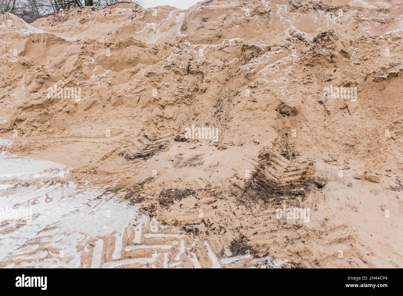 A large pile of sand of natural industrial material is stored outdoors ...