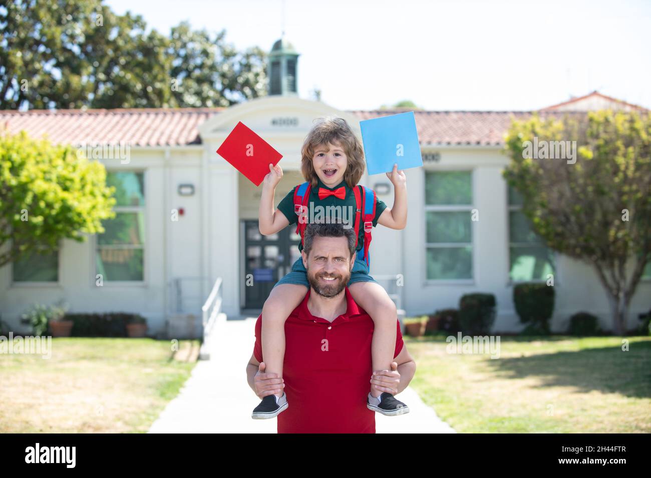 Father and son walking trough school park. Man giving son piggyback ...