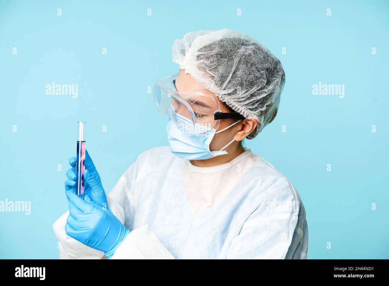 Lab worker mixing chemicals in sample test tube, wearing personal ...