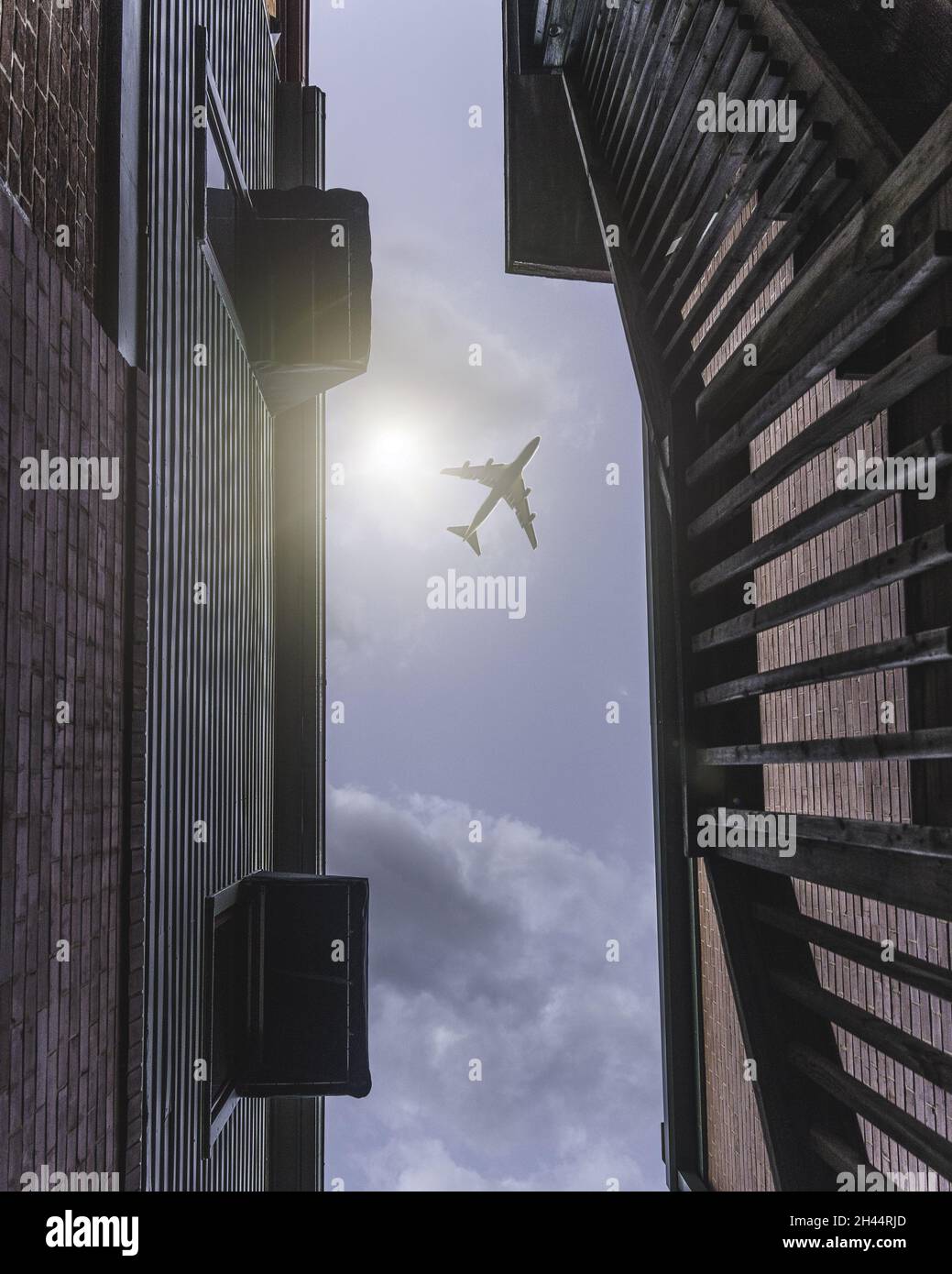 A vertical shot of an airplane flying in a sunny sky visible between ...