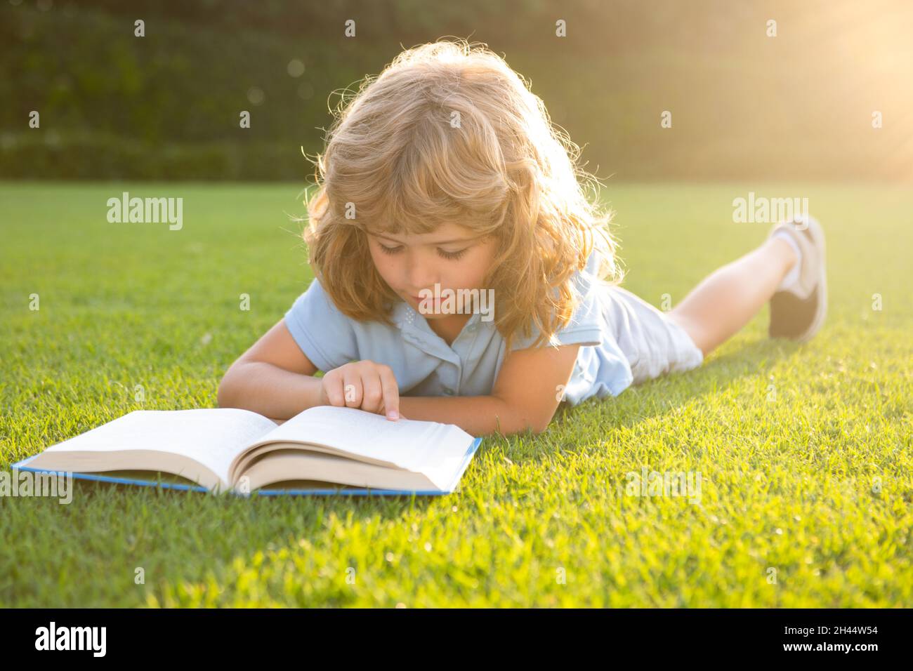 Smart clever Kids. Child relax in the holiday. Kid read books on grass ...
