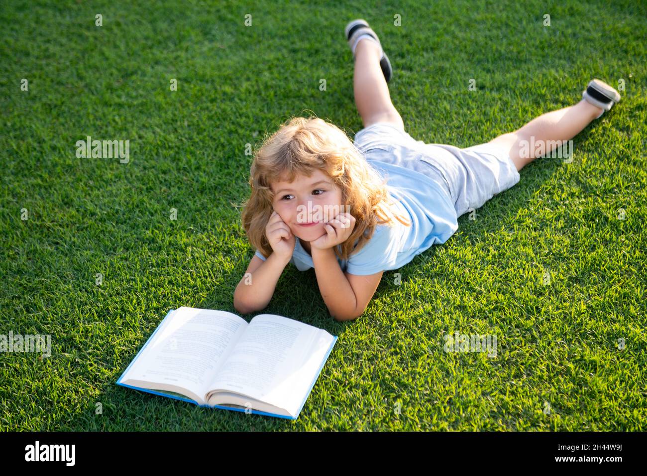 Child relax in the holiday. Kid read books on grass background. Concept ...
