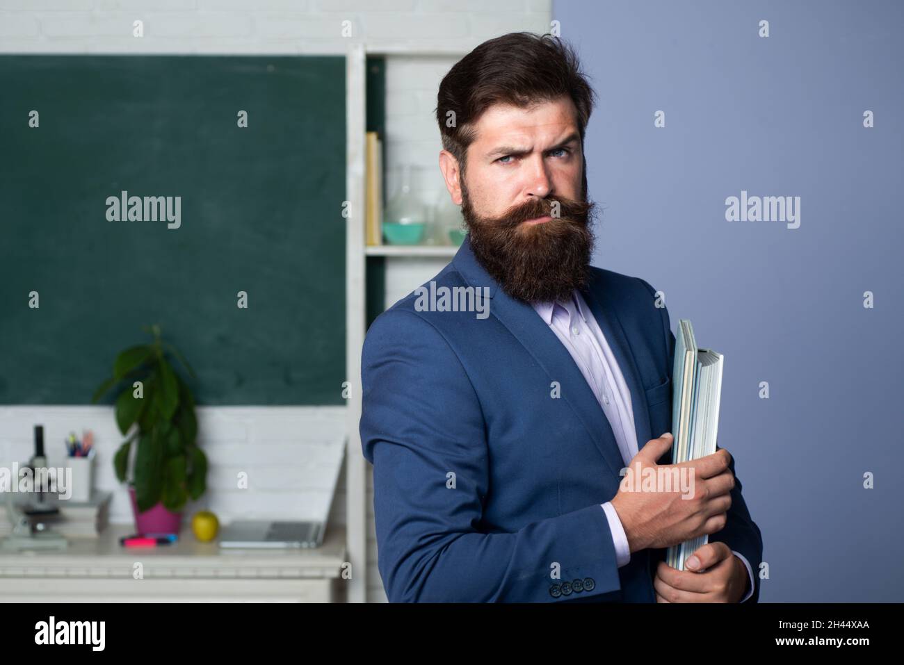 Portrait of teacher in classroom. Handsome bearded man near blackboard ...
