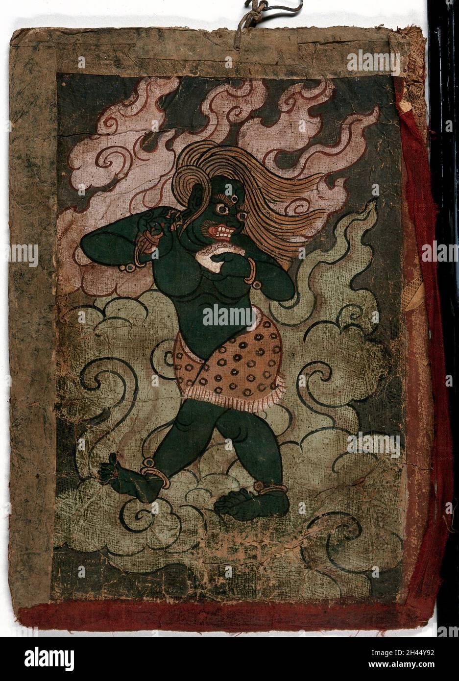 A green Tibetan demon (?) holding a skull cup and a vajra in its hand ...