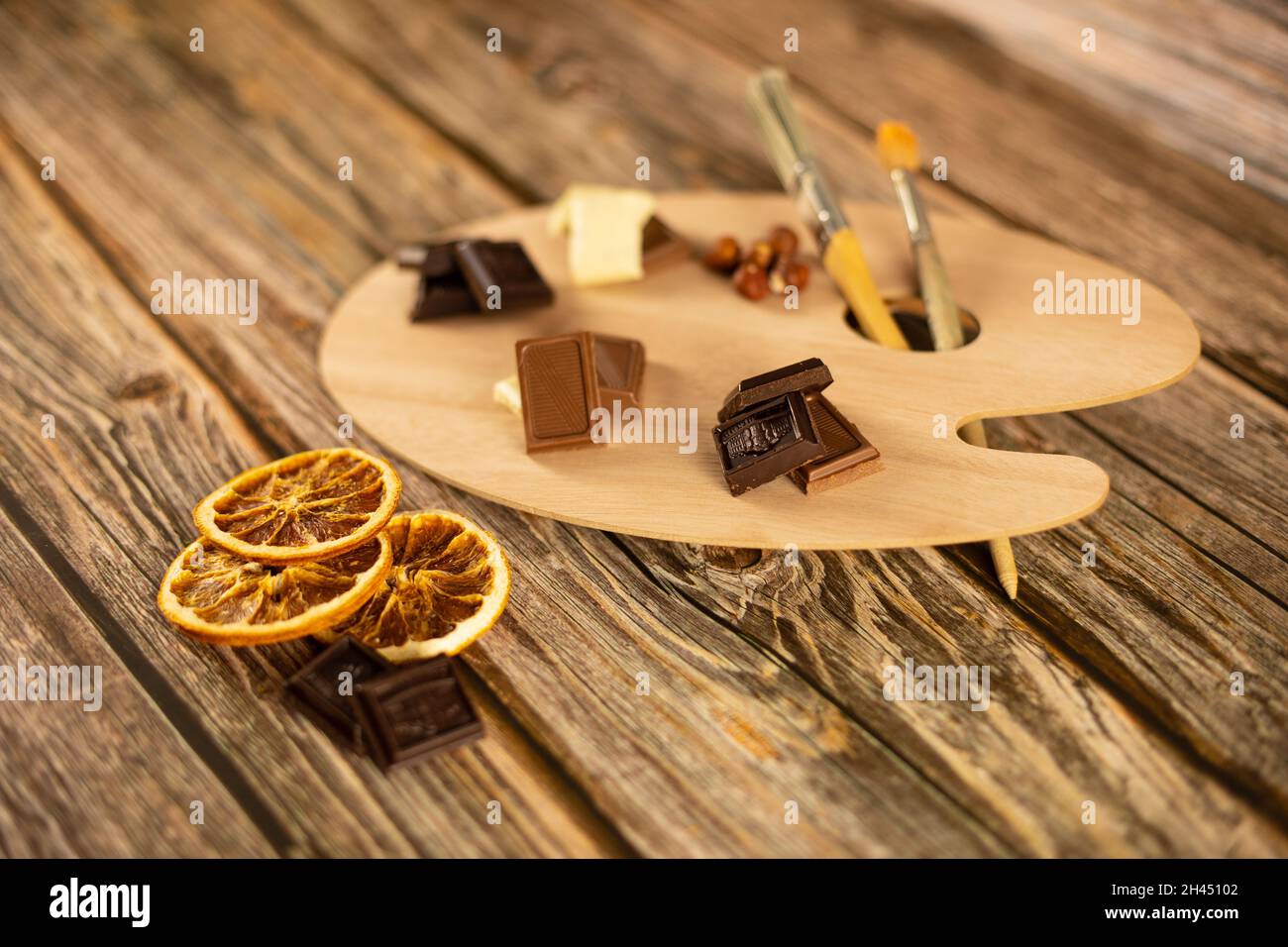 Assorted chocolates are set on an artistic palette against a warm ...