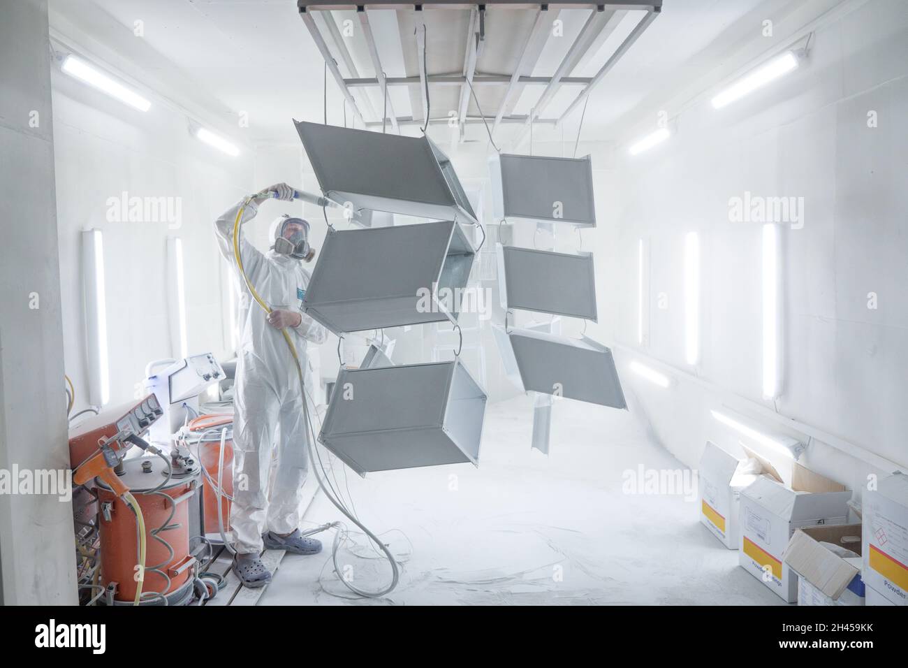 Coveralls worker with spray gun painting steel parts in painting ...