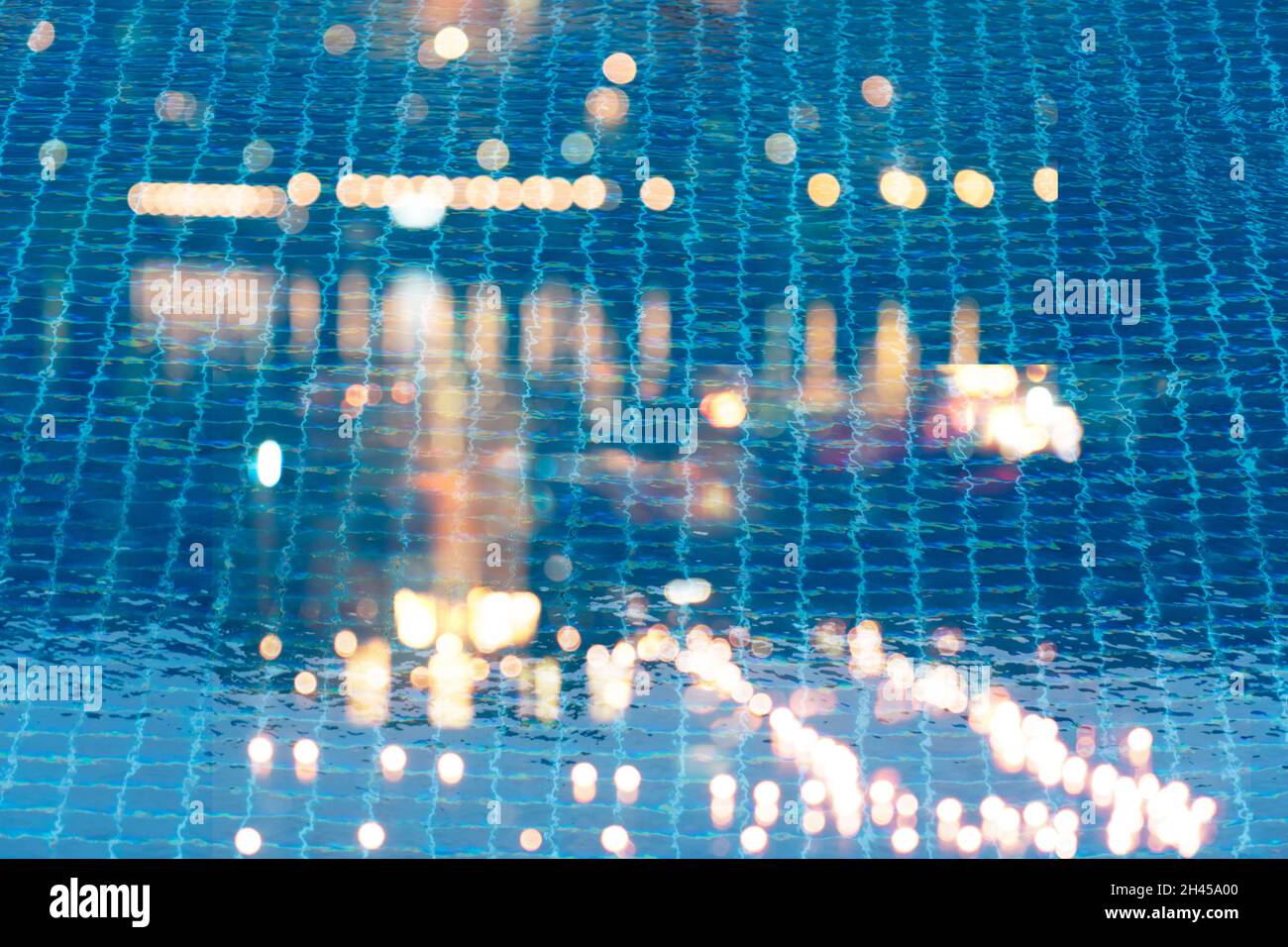 blur orange light of bar or pub reflection on blue water swimming pool ...