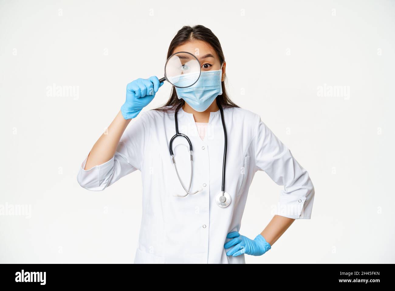 Funny asian woman doctor looks through magnifying glass at patient ...