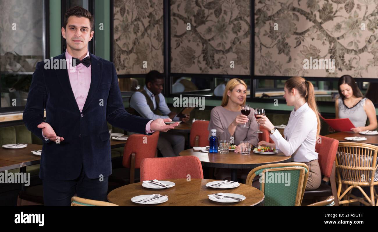 Smiling waiter meeting restaurant guests Stock Photo - Alamy