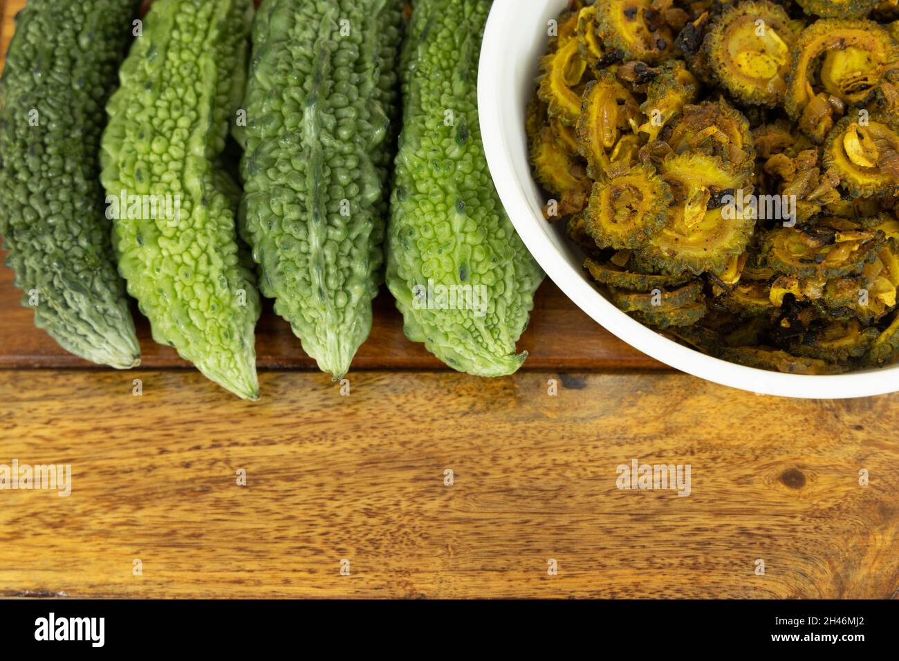 Cooked bitter gourd and raw bitter gourd kept alongside each other ...