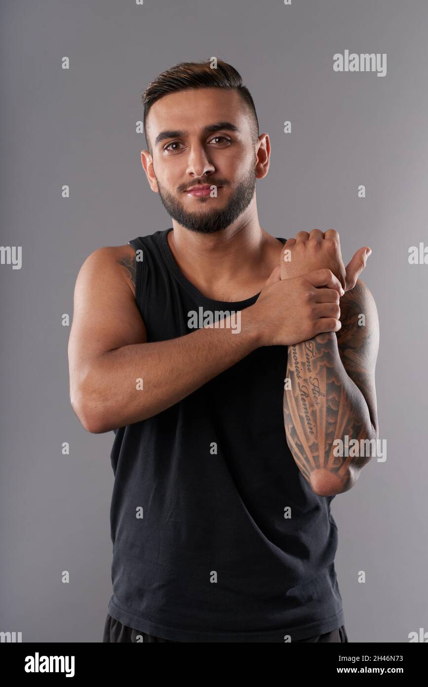 Portrait of positive fit young man stretching arm when warming up ...