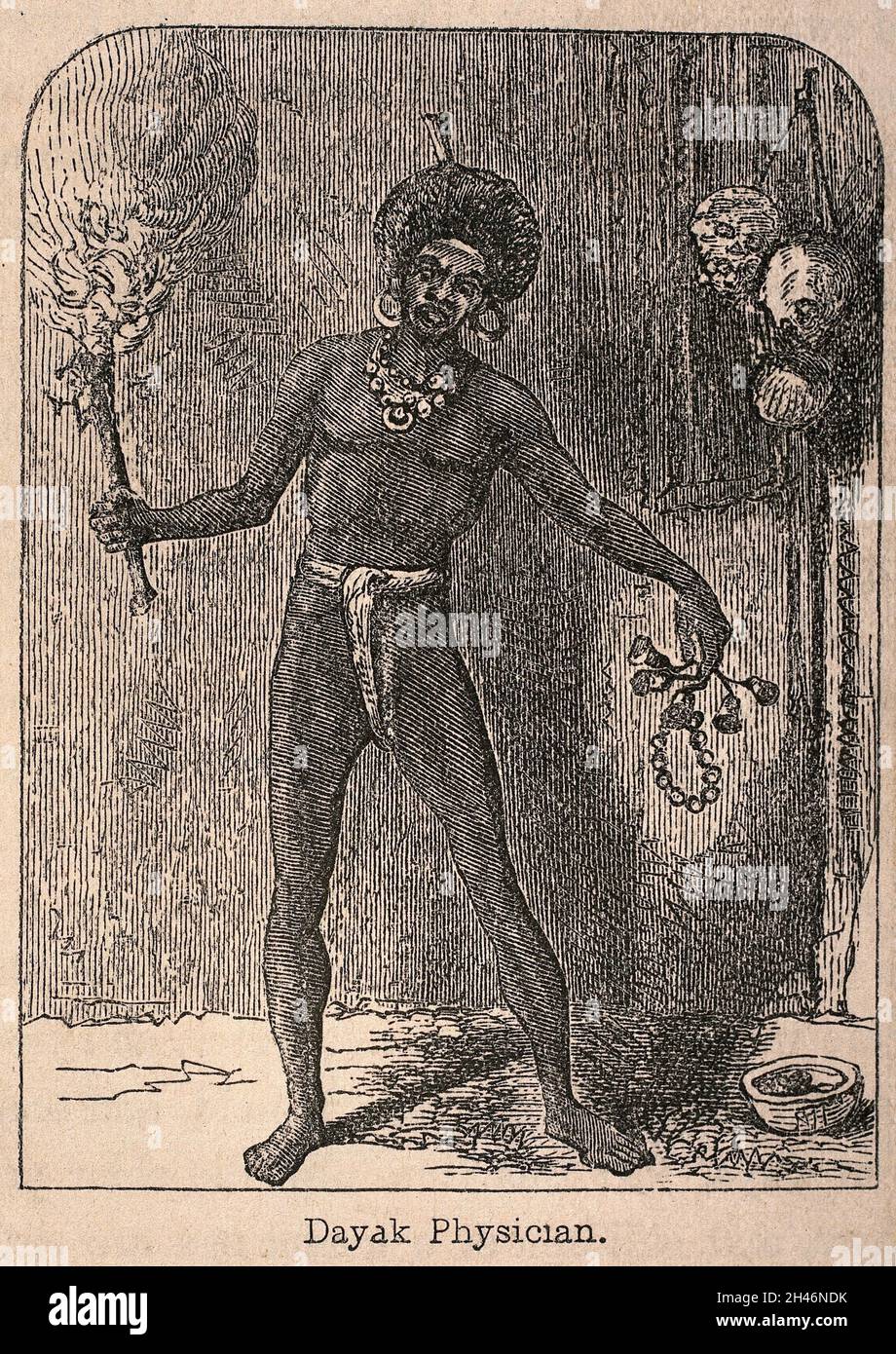 A Dayak shaman or medicine man holding a flaming torch and some charms ...