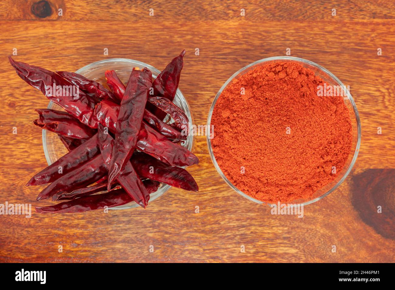 Top view of dry red chillies and red chilli powder bowls kept side by ...