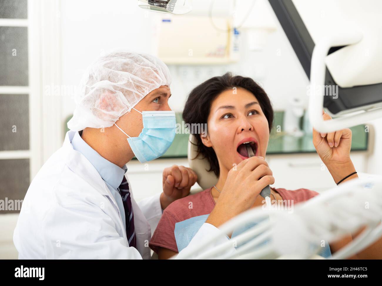 Dentist uses modern equipment and a computer to check patient teeth ...