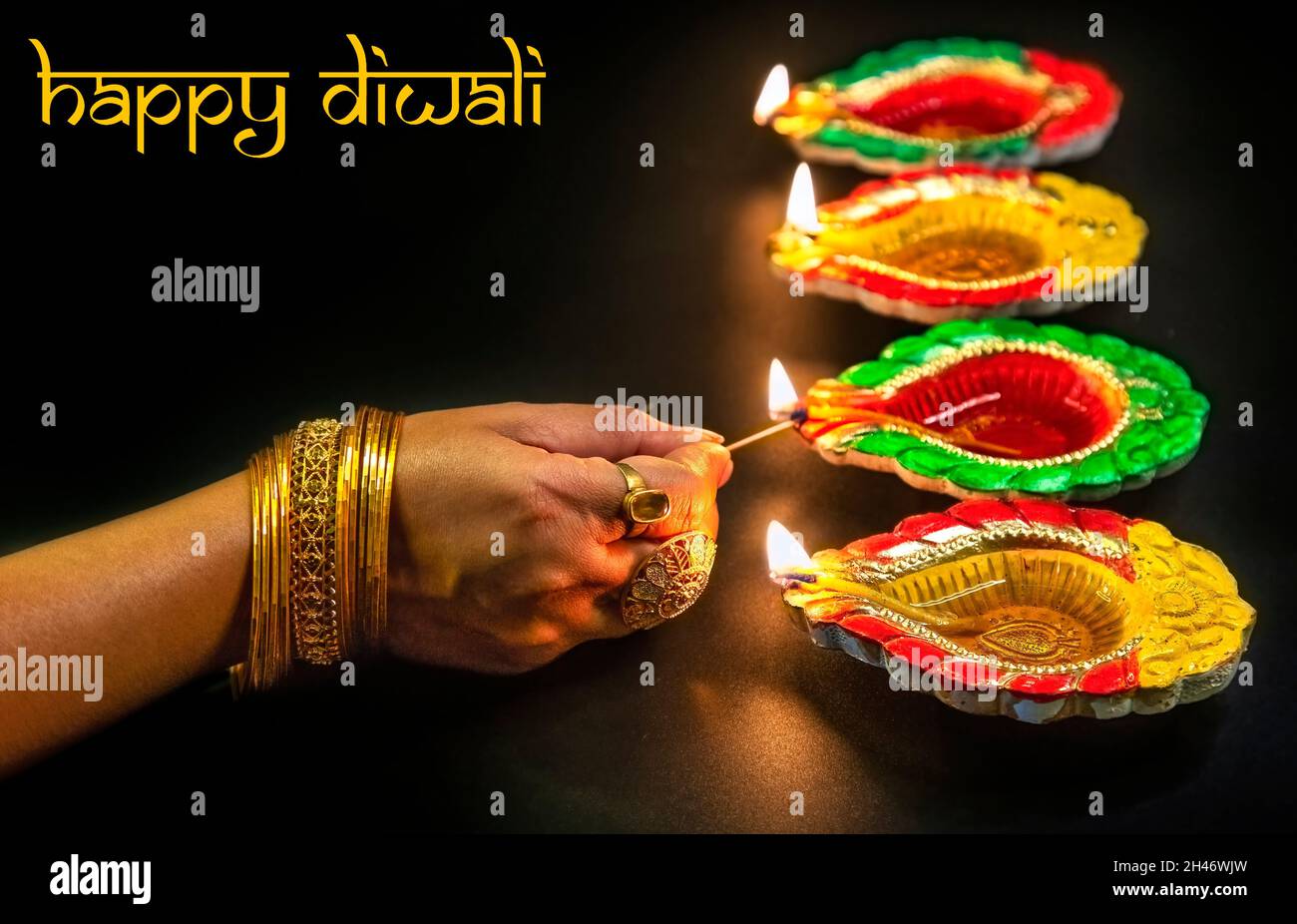 Woman hand lighting traditional clay Diya lamps with floral decoration ...