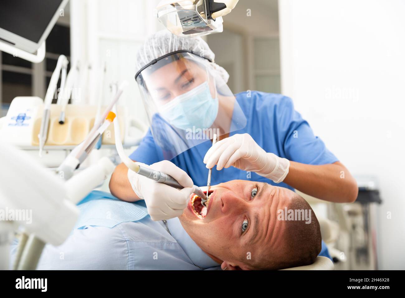 Female dentist drilling tooth to male patient Stock Photo - Alamy