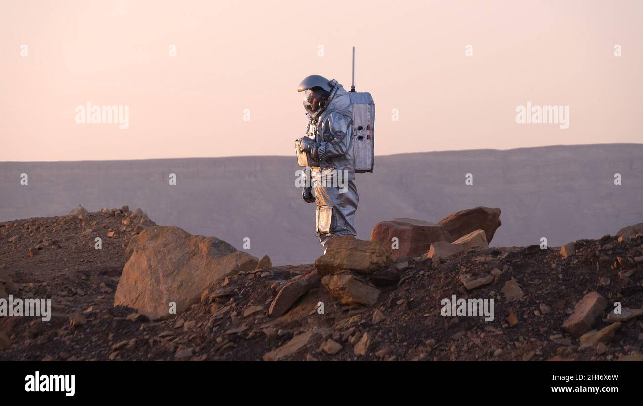 An analog astronaut, clad in a specialized spacesuit, walks around a ...