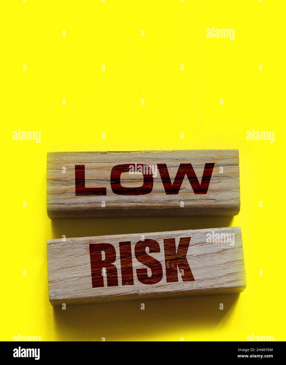 Low risk words wooden blocks on yellow. Business investment risks ...