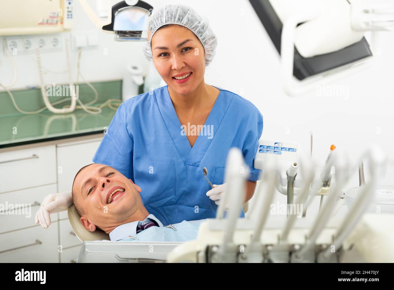 Dentist and happy patient sitting in dental chair Stock Photo - Alamy