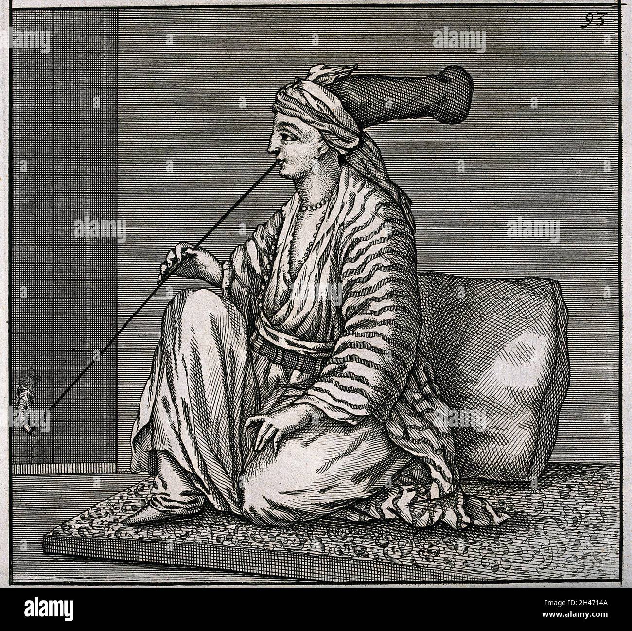 A young Jewish woman with long-crowned turban kneels on a mat smoking ...