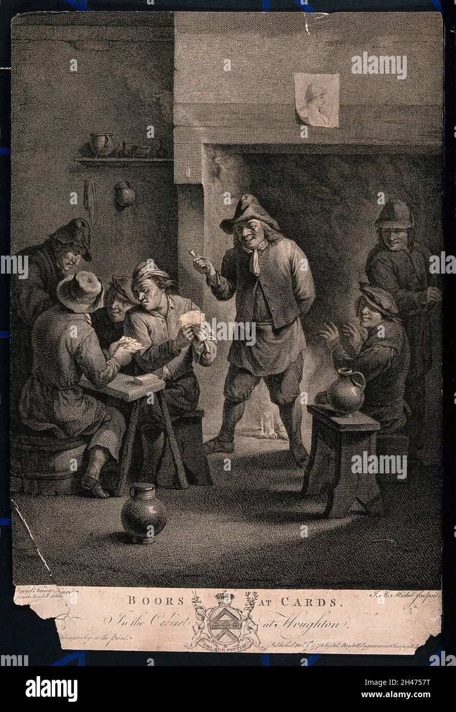 Four men sit at a table playing cards, others watch as they stand ...