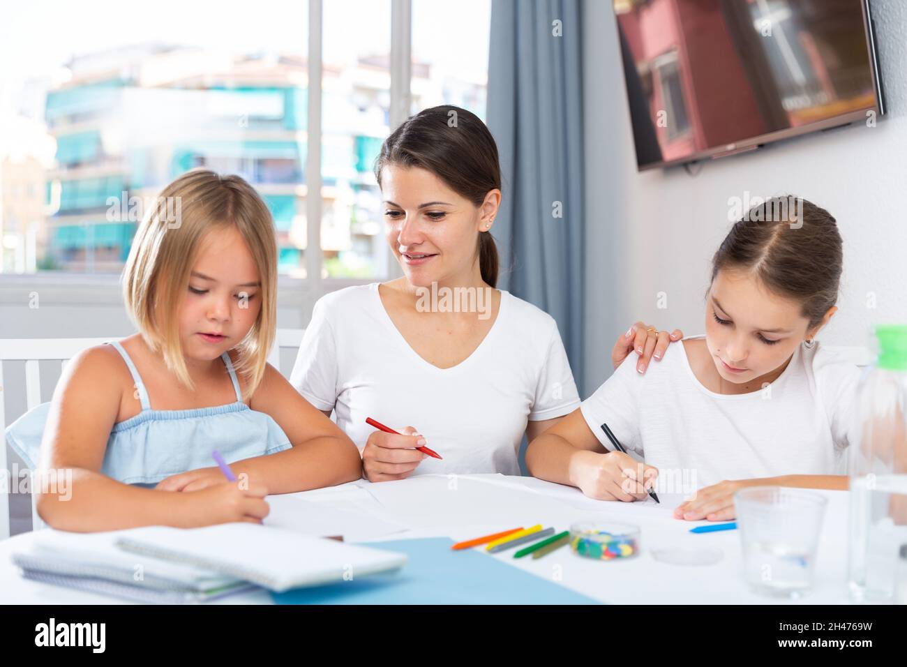 Young woman and two daughters drawing together Stock Photo - Alamy