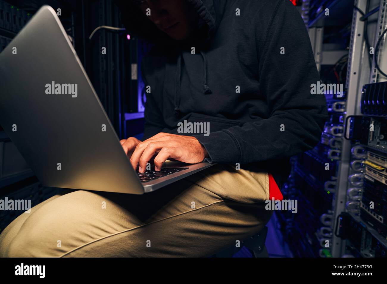 Hacker typing on his laptop in dark server room Stock Photo - Alamy