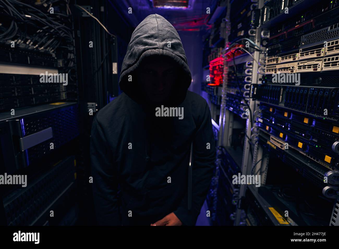 Male hacker standing in dark server room Stock Photo - Alamy