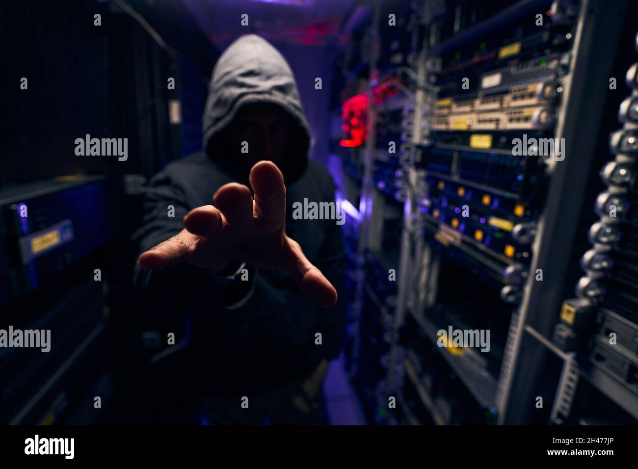 Guy in hoodie standing in dark server room Stock Photo - Alamy