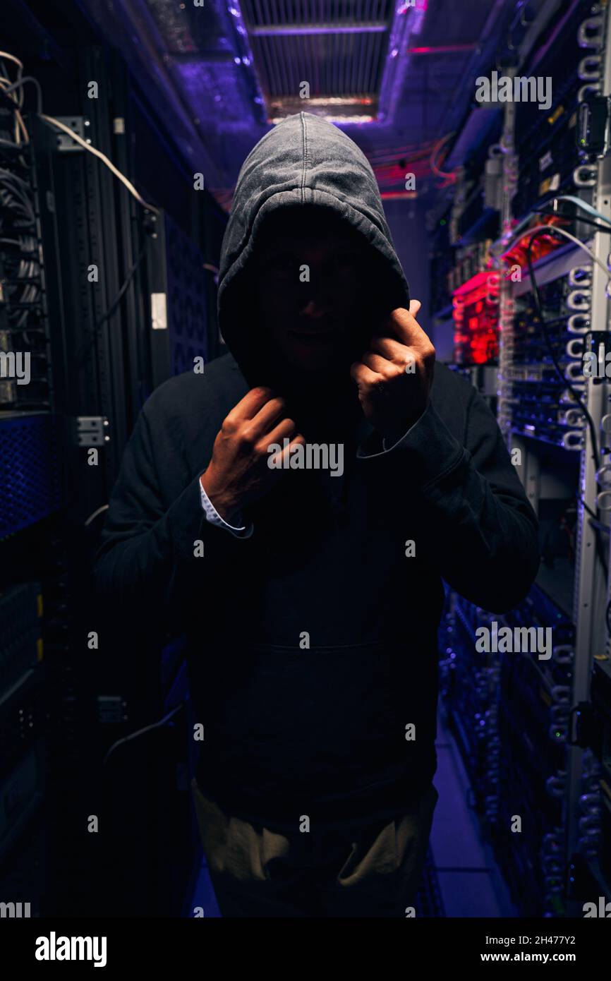 Hacker in server room attempting to cover his face Stock Photo - Alamy